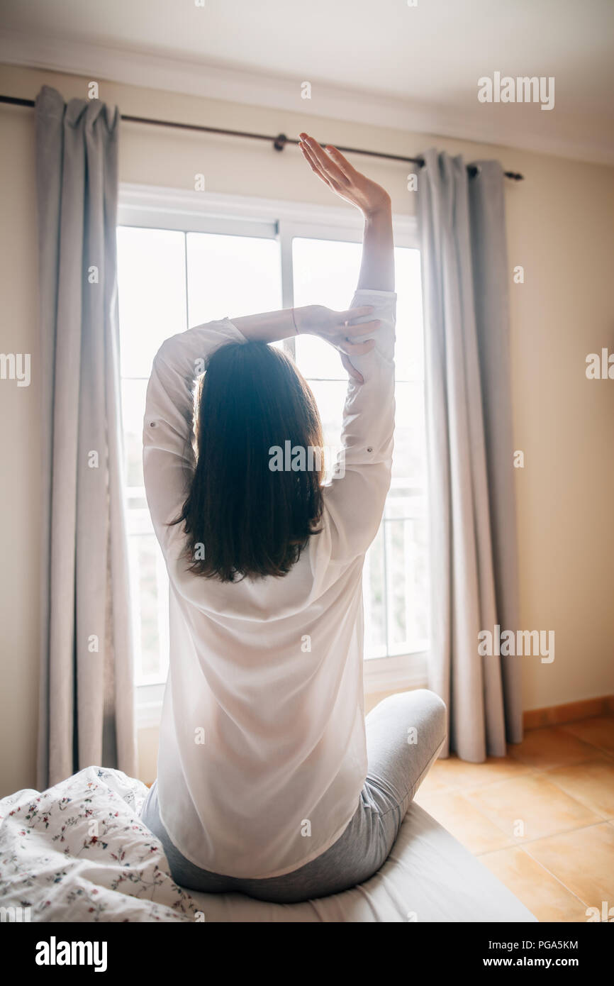 Pretty woman stretching in bed after wake up, back view Stock Photo - Alamy