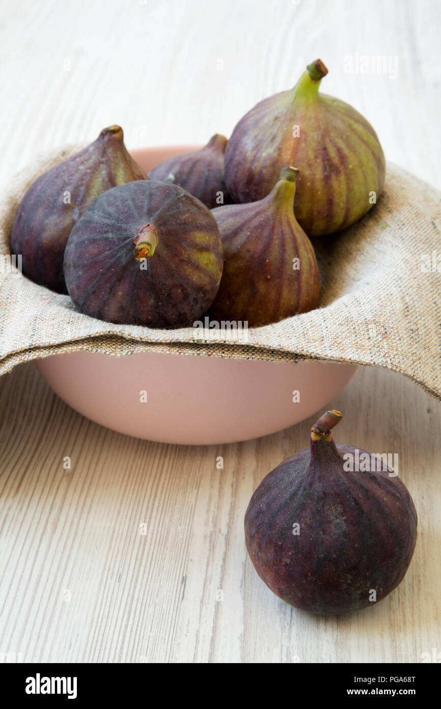Fresh figs in a pink bowl on a white wooden background, side view ...