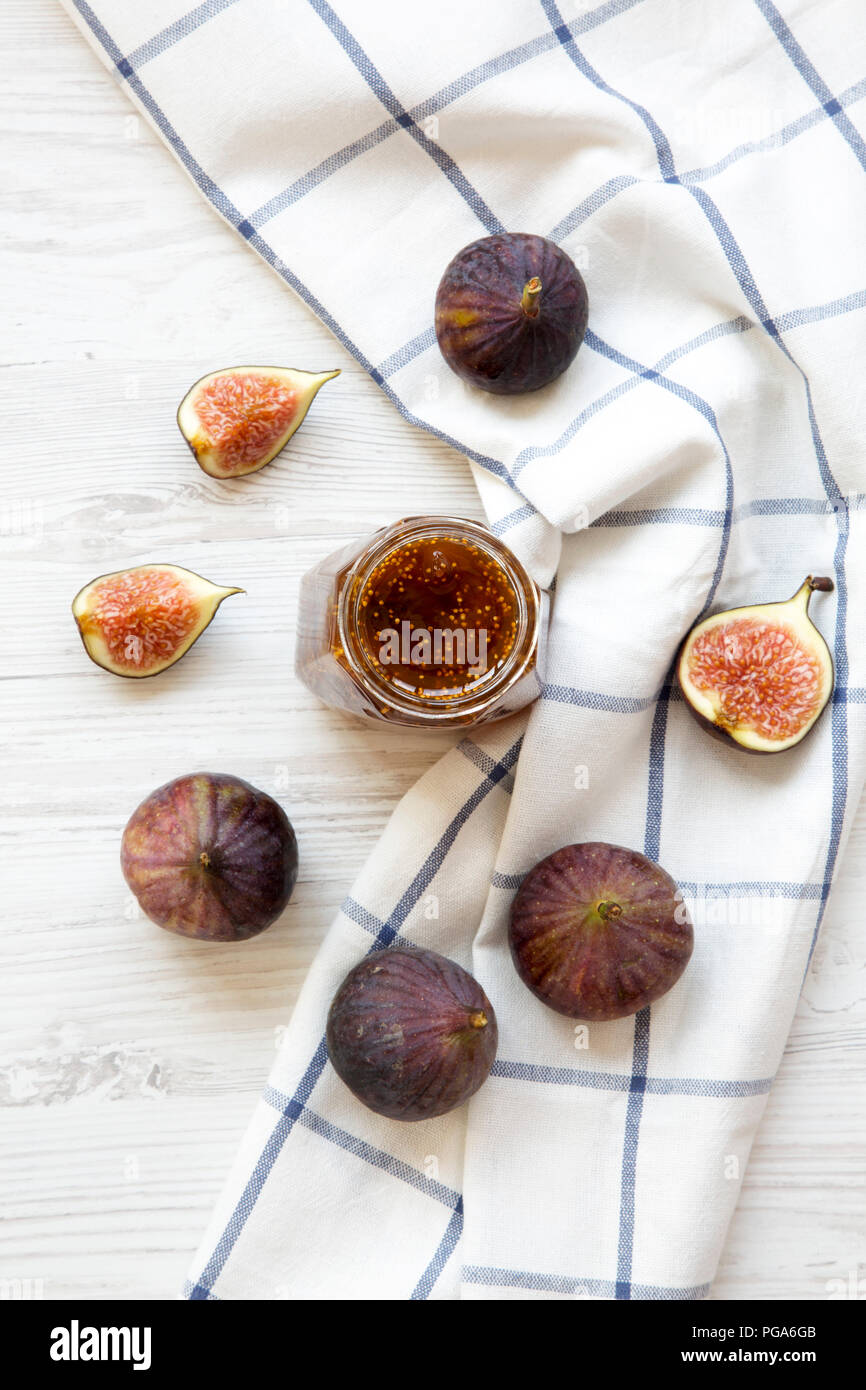 Fig jam in glass jar and fresh figs on white wooden table, overhead ...