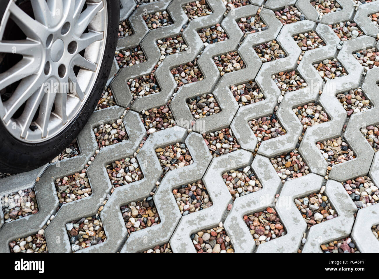 Alloy car wheel on wet openwork concrete pavement filled with colorful ...