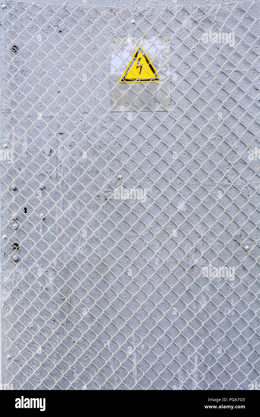 Danger of electrocution yellow sign on gray background with metal wire ...