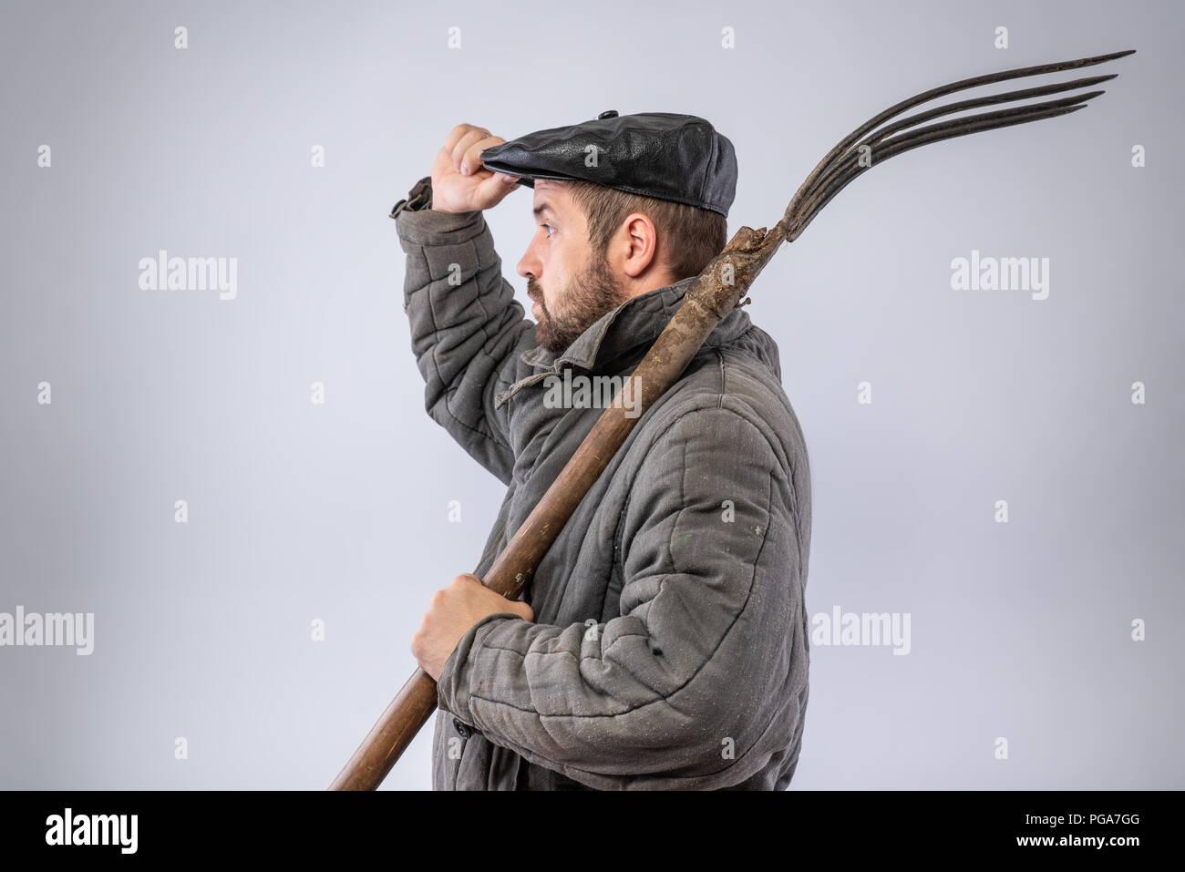 Man with pitchfork on his shoulder gives greeting gesture, dressed in ...