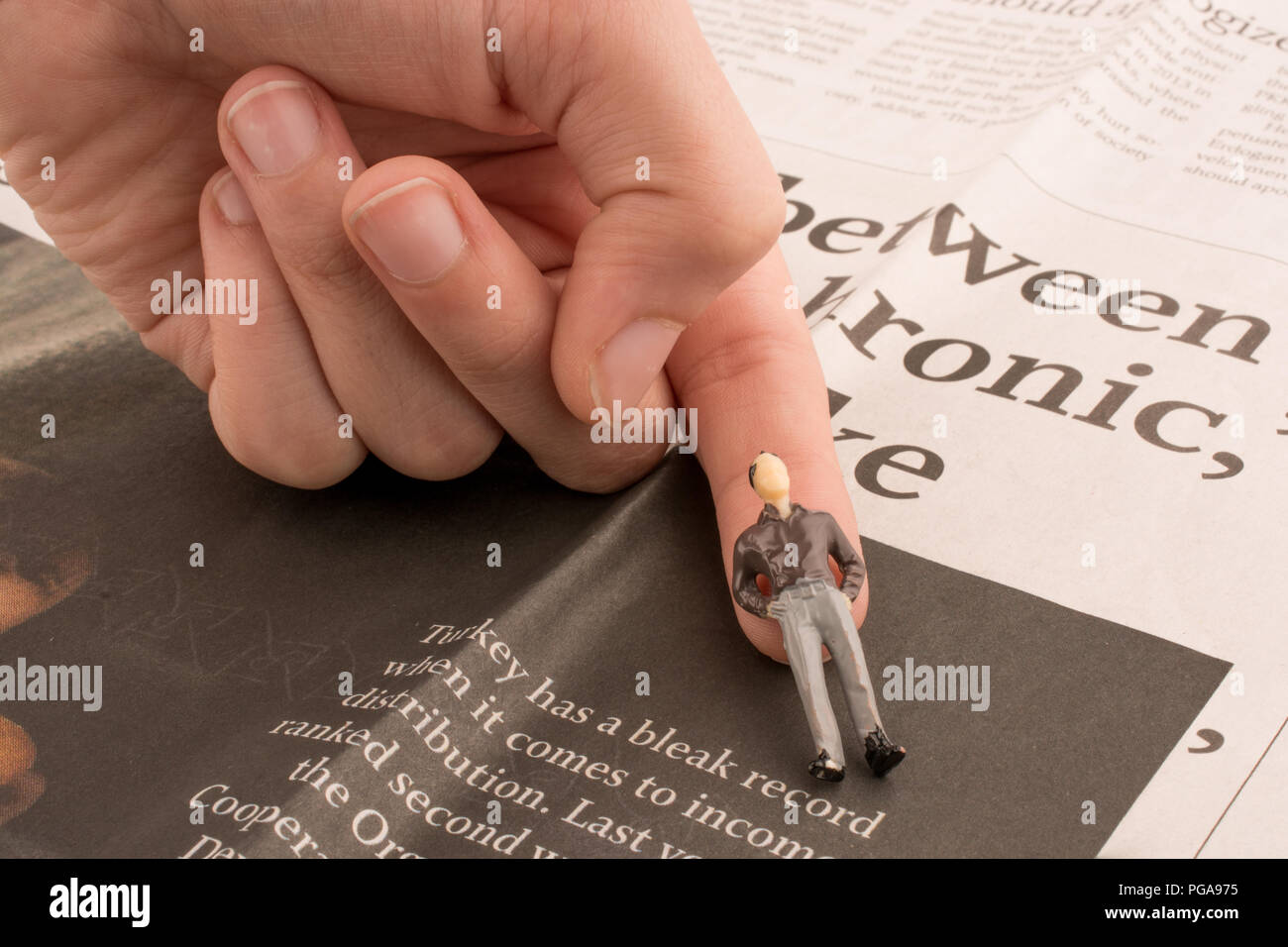 Hand holding a human figure on a newspaper Stock Photo - Alamy