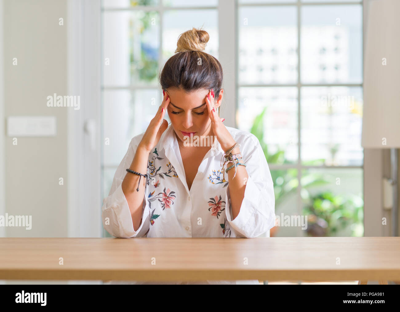 Young woman at home with hand on head for pain in head because stress ...