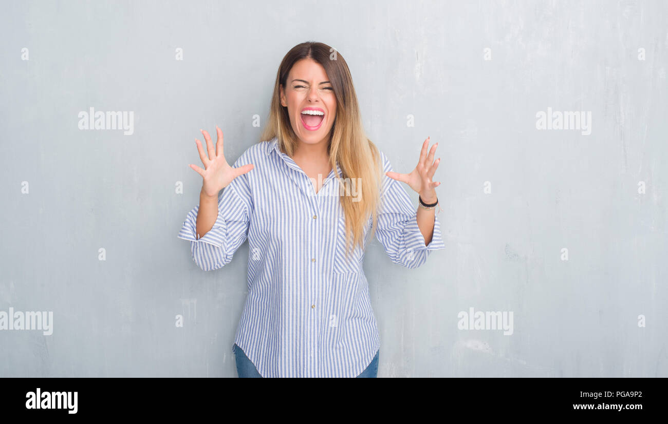 Young adult woman over grey grunge wall wearing fashion business outfit ...