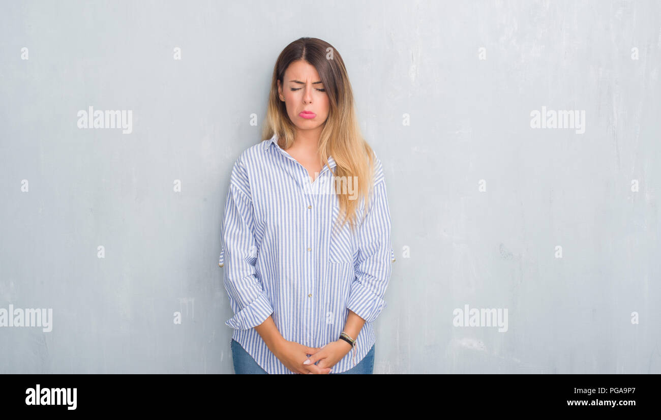 Young adult woman over grey grunge wall wearing fashion business outfit ...