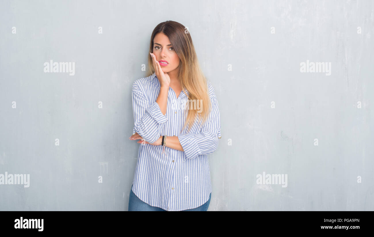 Young adult woman over grey grunge wall wearing fashion business outfit ...