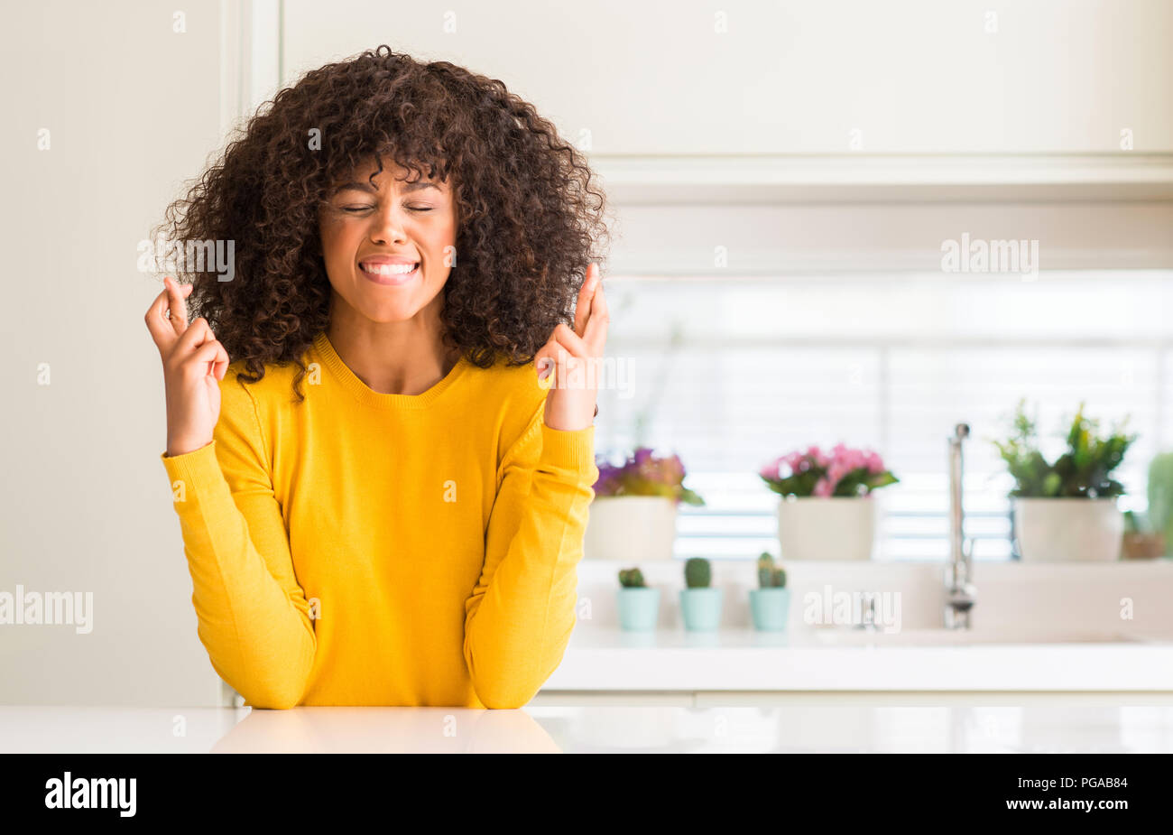 African american woman wearing yellow sweater at kitchen smiling ...
