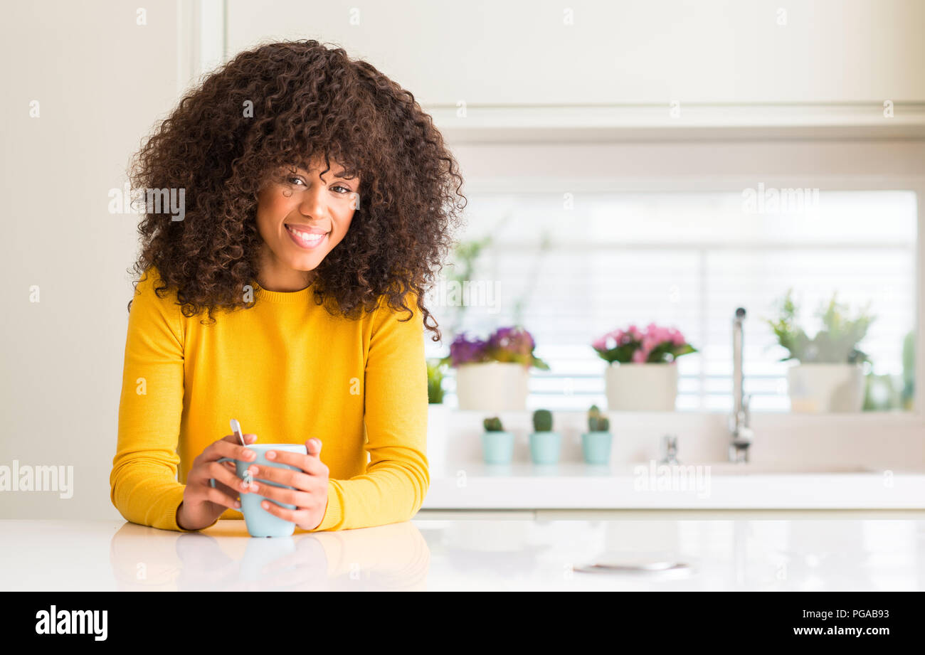 Beautiful african american woman holding a cup of coffee at home with a ...