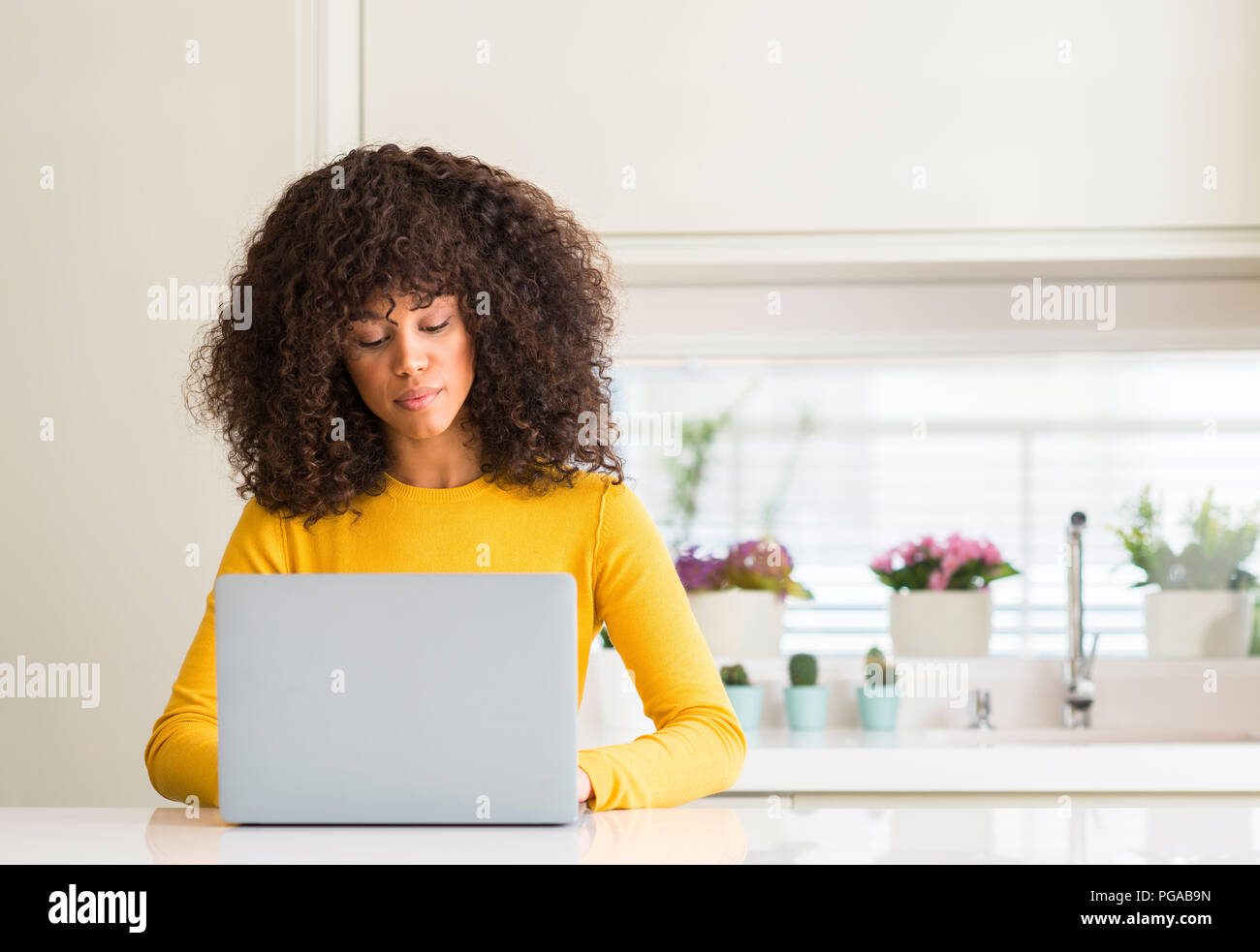 African american woman using computer laptop at kitchen with a ...
