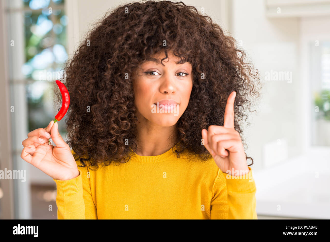 African american woman eating red hot chili pepper surprised with an ...