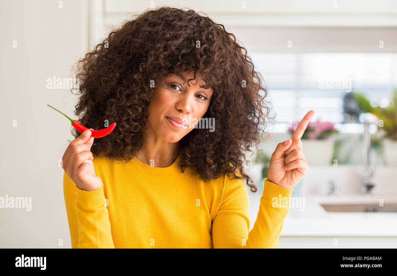 African american woman eating red hot chili pepper very happy pointing ...