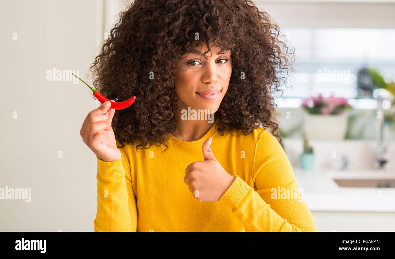African american woman eating red hot chili pepper happy with big smile ...