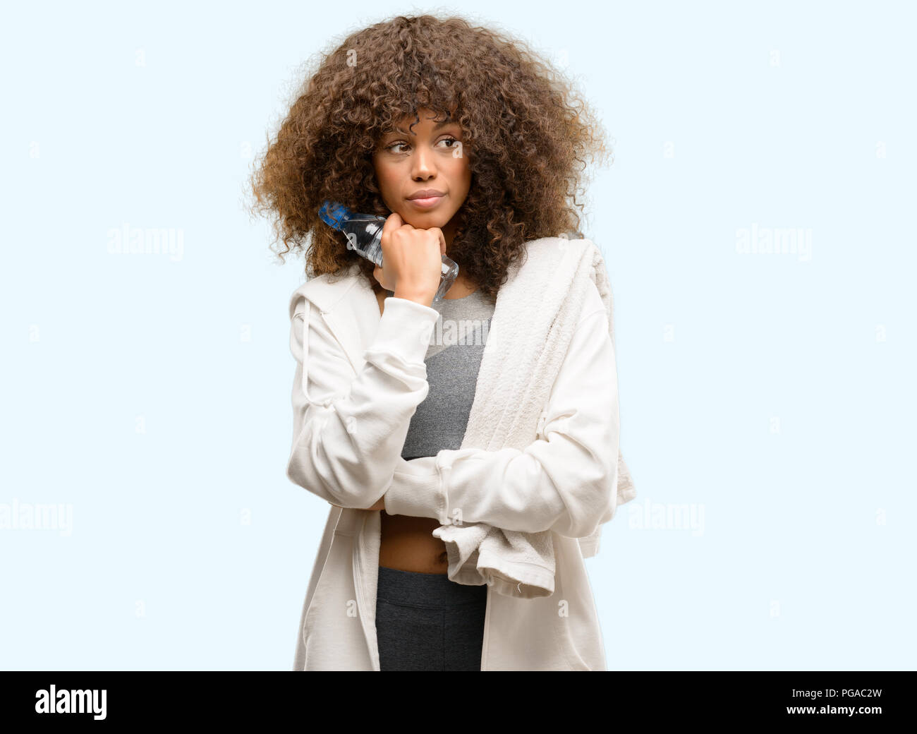 African american fitness woman holding water bottle serious face ...
