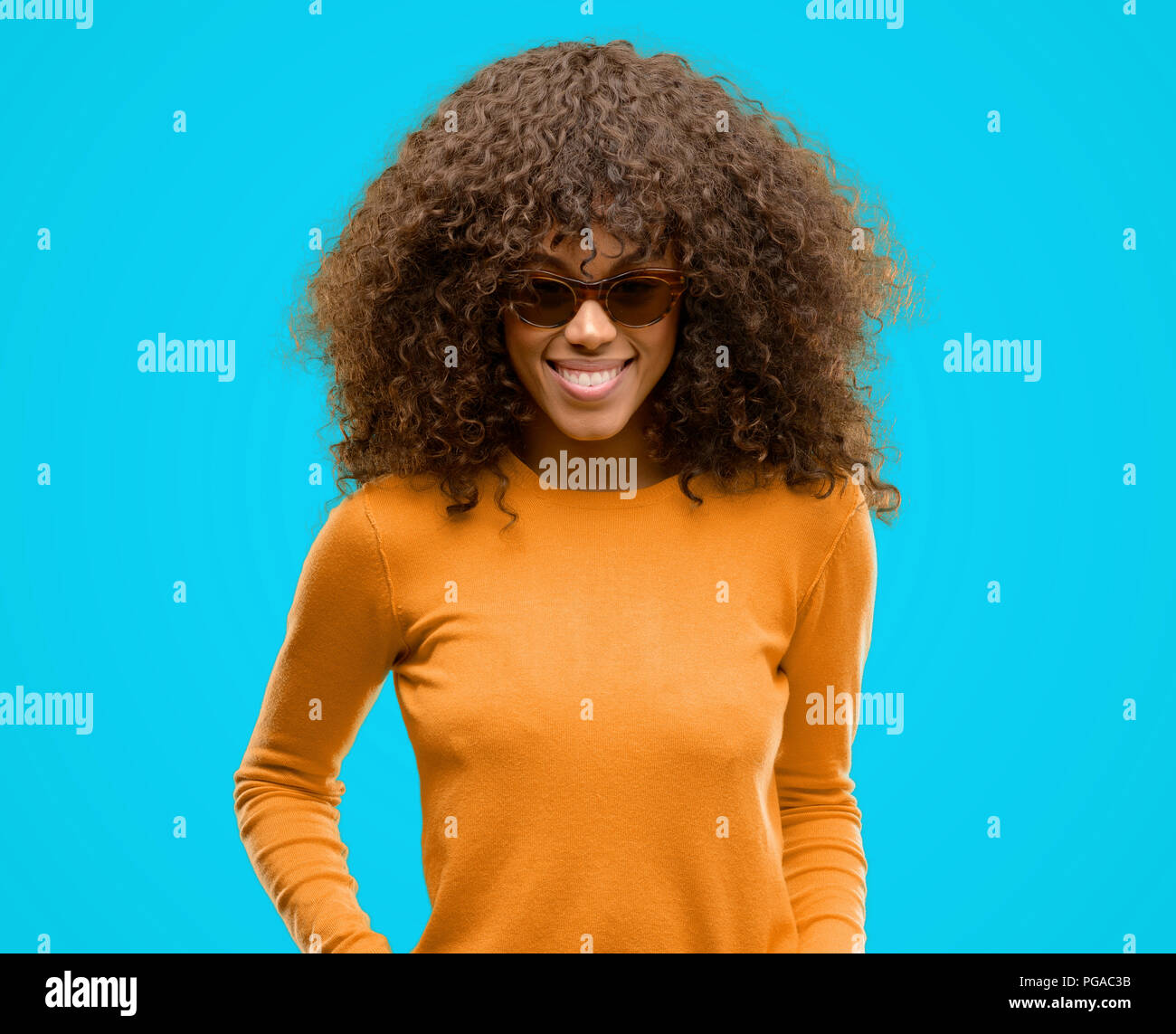 African american woman wearing an orage sweater with a happy face ...
