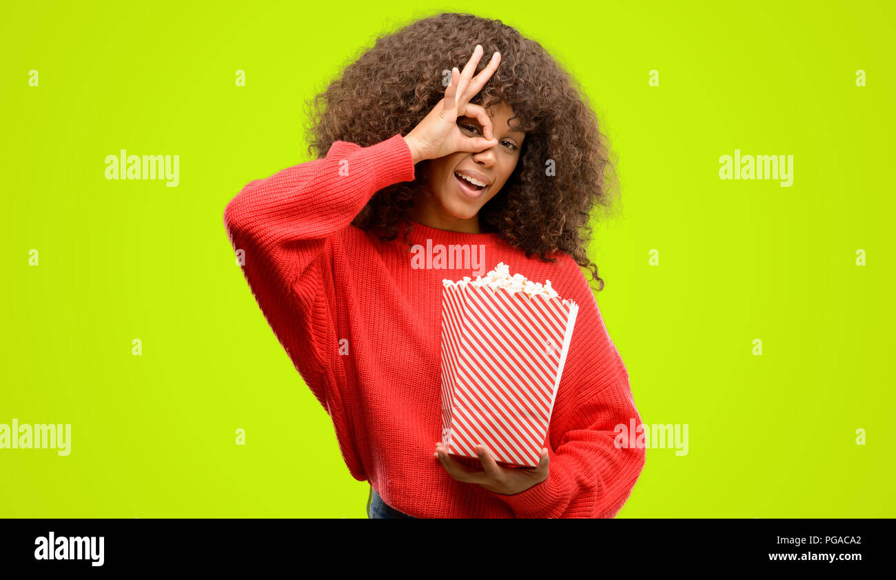 African american woman eating popcorn with happy face smiling doing ok ...