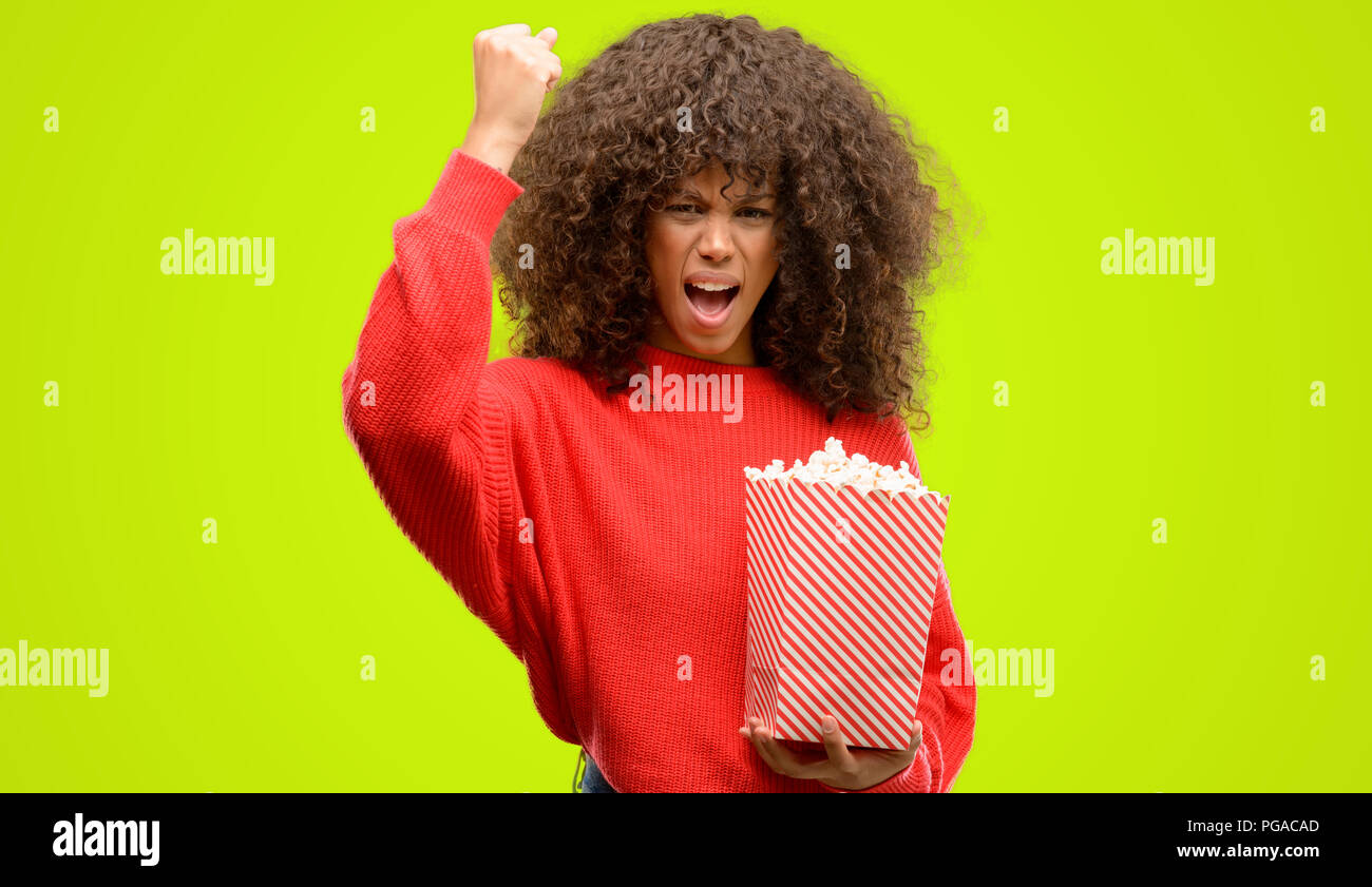 African american woman eating popcorn annoyed and frustrated shouting ...