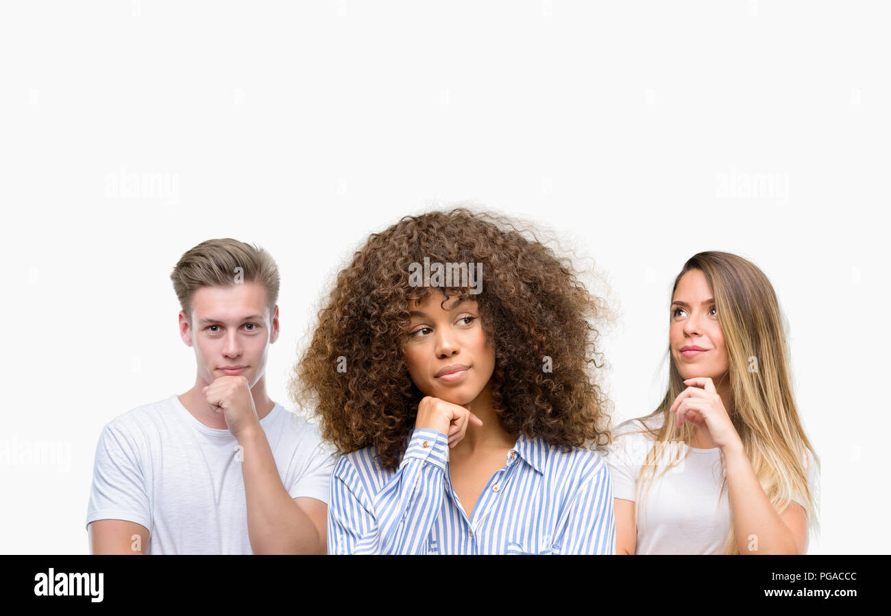 Group of young people over white background serious face thinking about ...