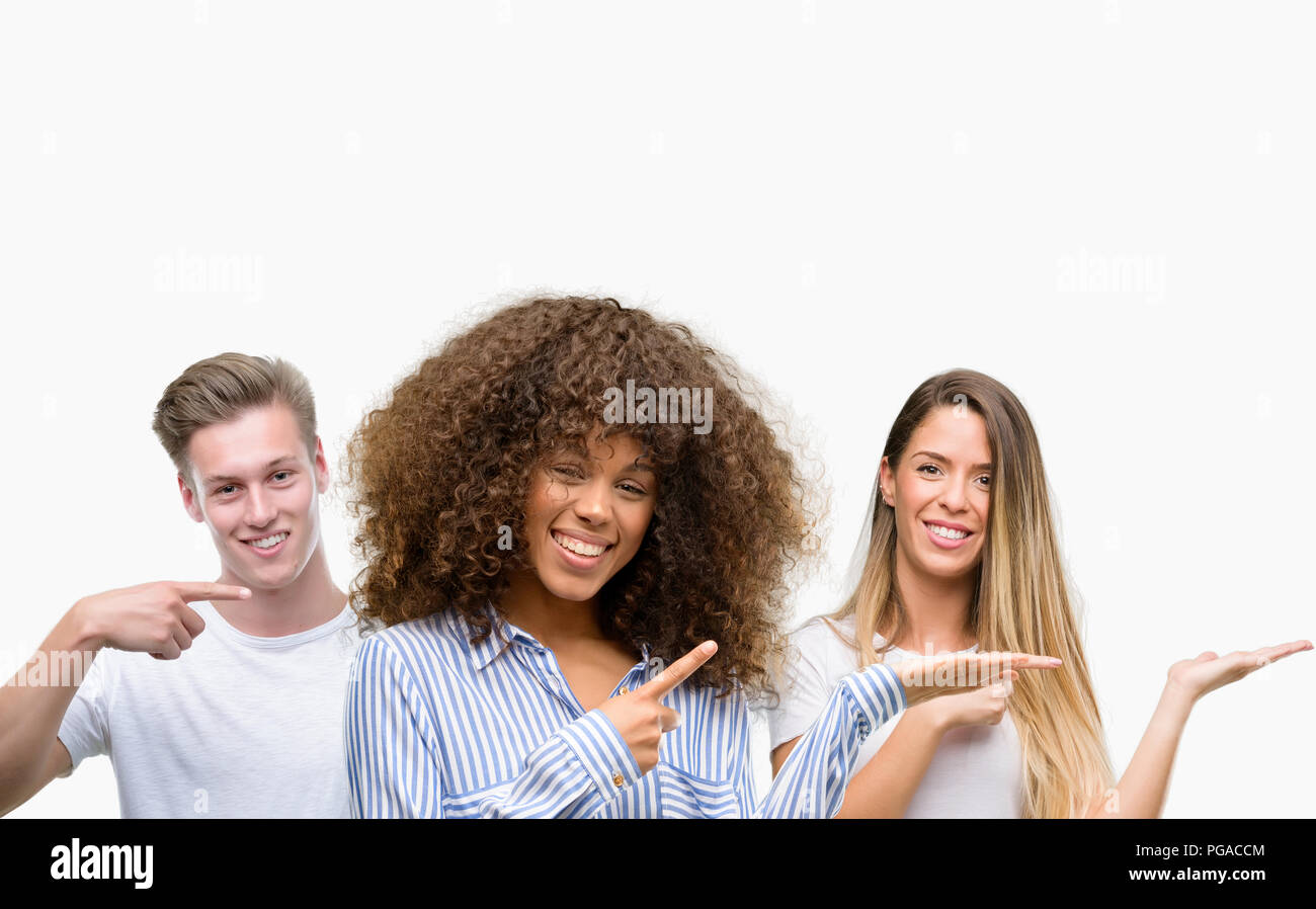 Group of young people over white background very happy pointing with ...