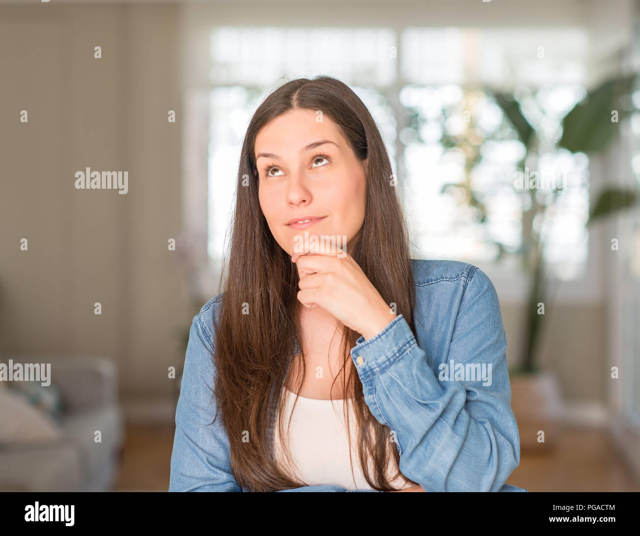 Young beautiful woman at home serious face thinking about question ...