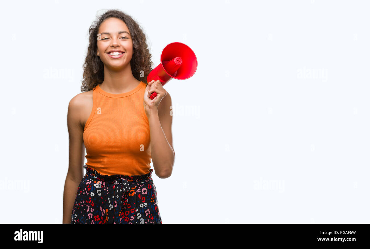 Young hispanic woman holding megaphone with a happy face standing and ...