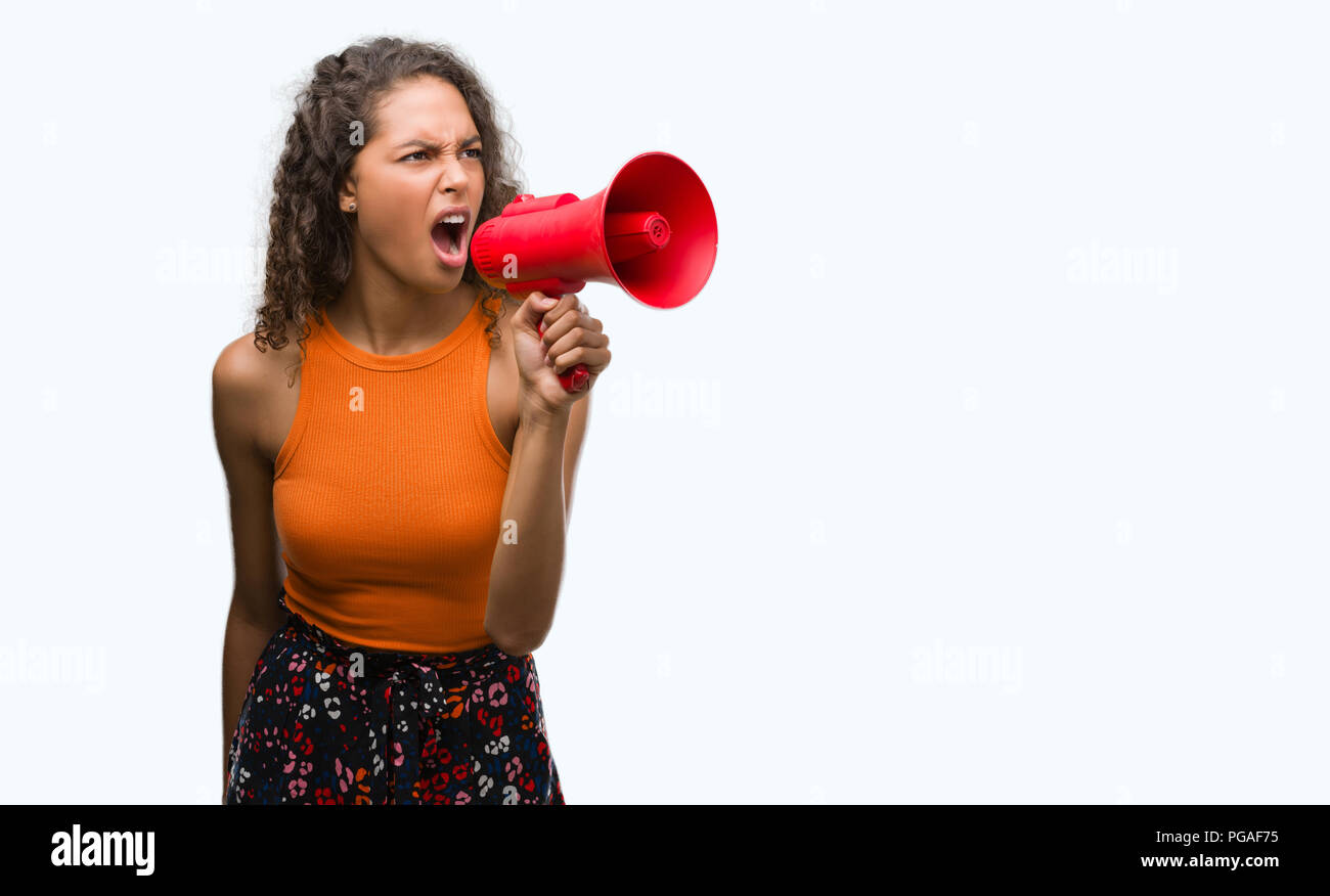 Young hispanic woman holding megaphone annoyed and frustrated shouting ...