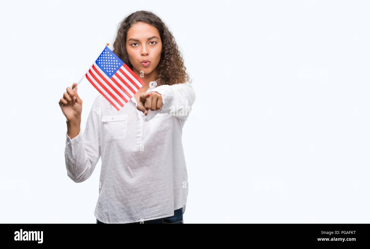 Young hispanic woman holding flag of United Estates of America pointing ...