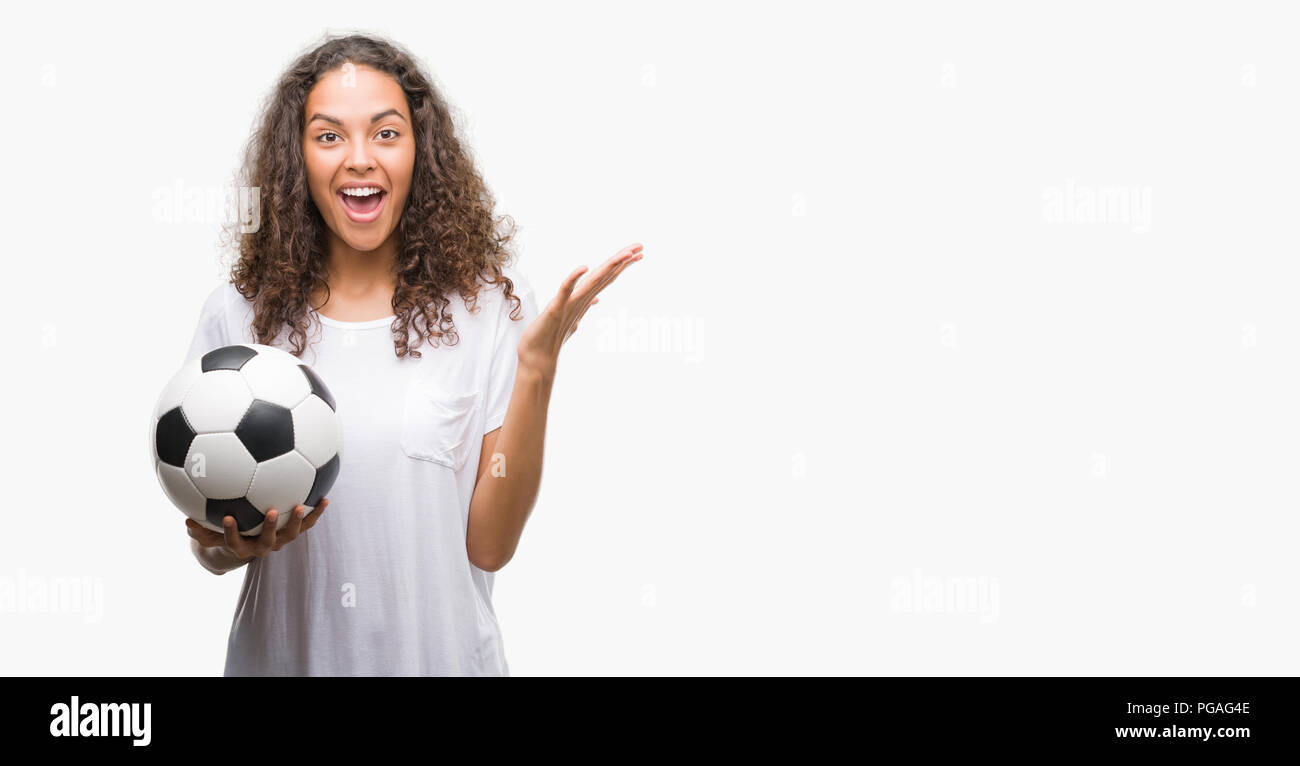 Young hispanic woman holding soccer football ball very happy and ...