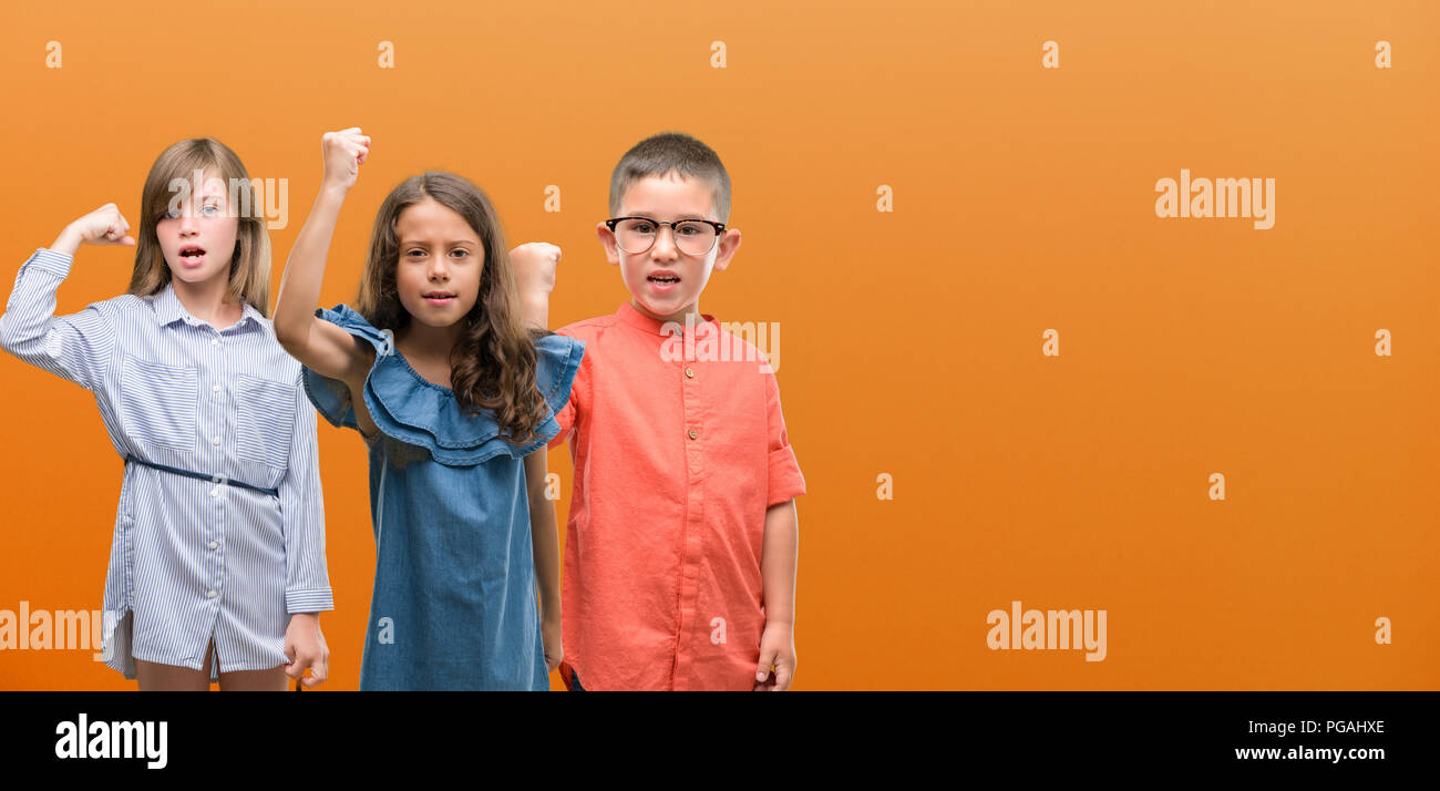 Group of boy and girls kids over orange background annoyed and ...