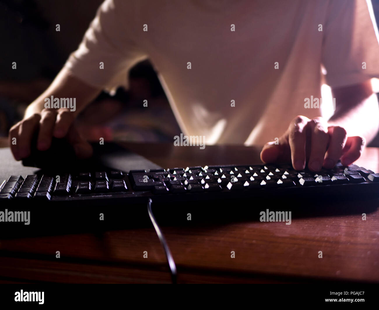 close up gamer hands on the keyboard playing video games in the night ...