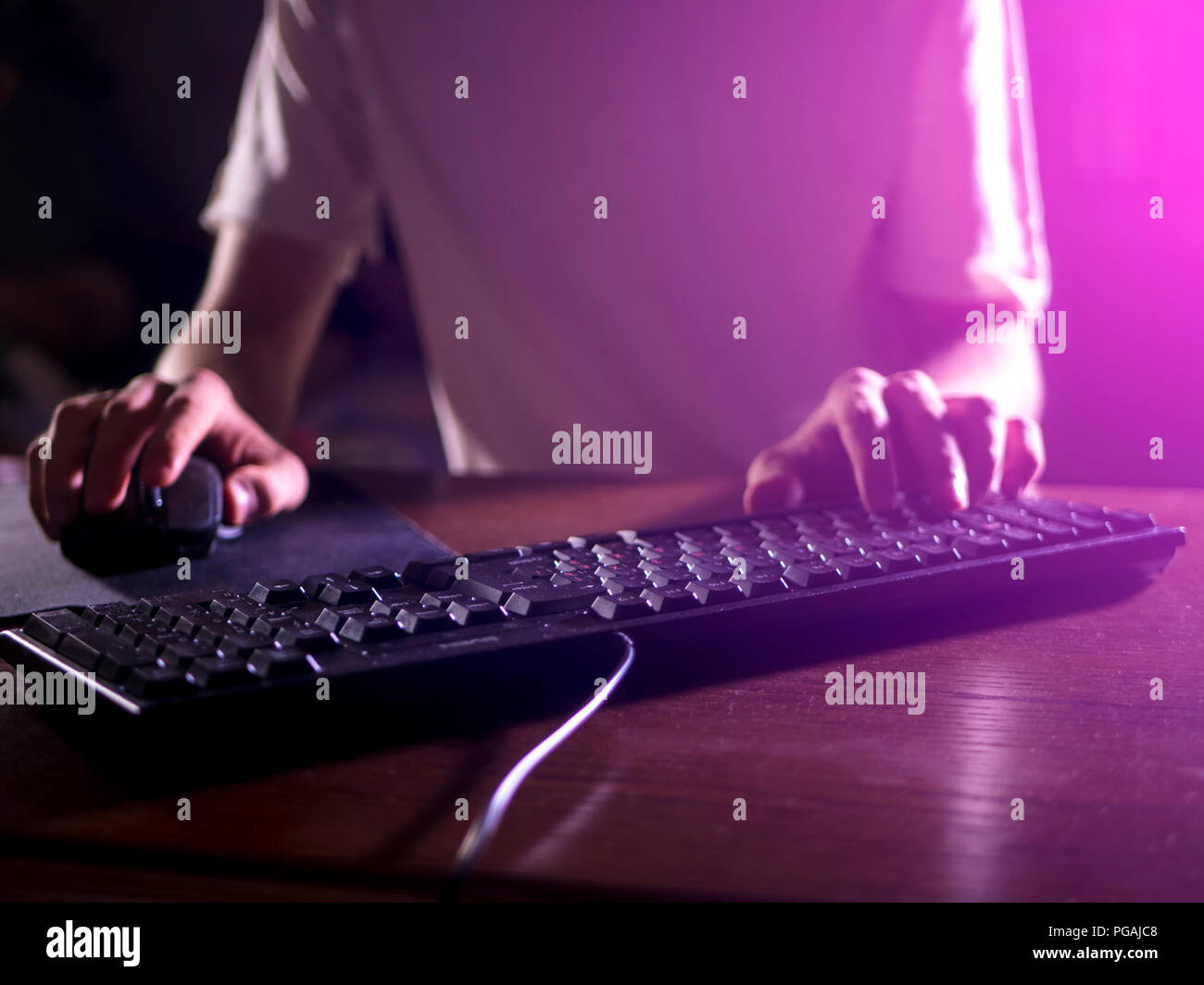 close up gamer hands on the keyboard playing video games in the night ...