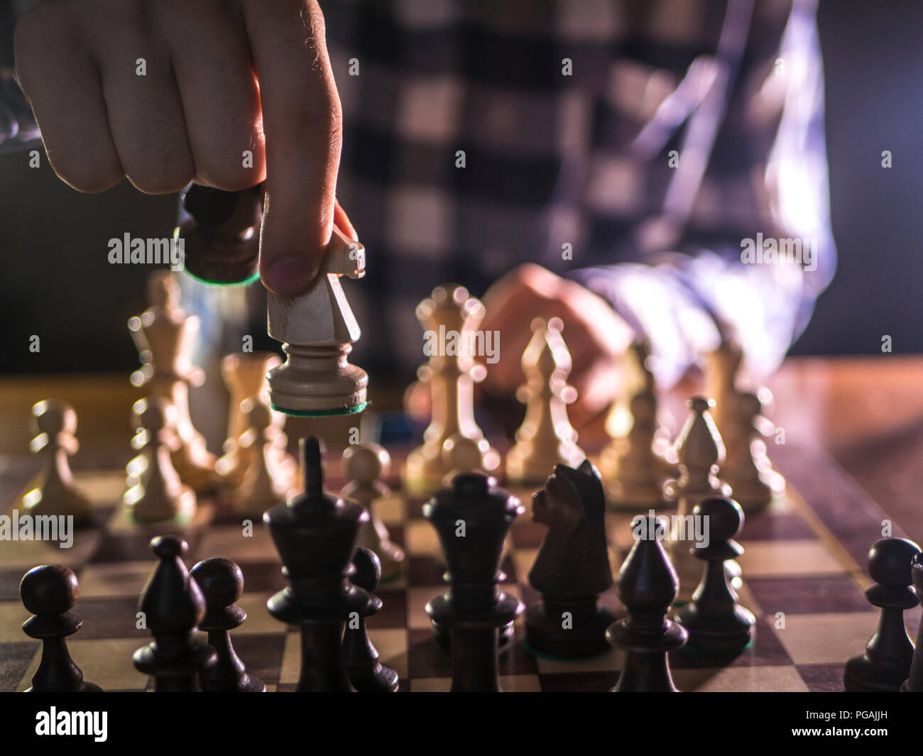 young male grandmaster hand making next move playing chess in dark ...
