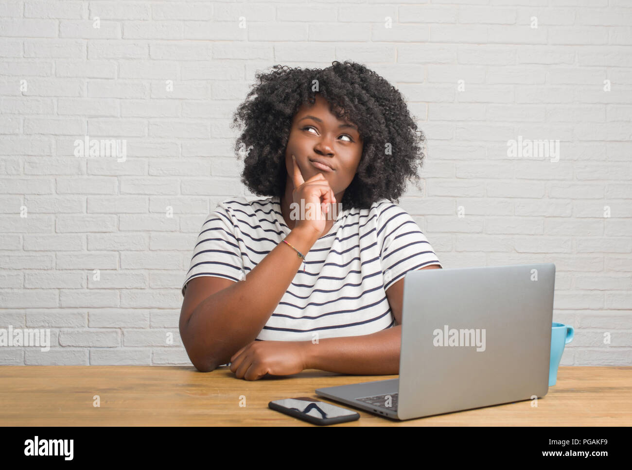 Young african american woman sitting on the table using computer laptop ...
