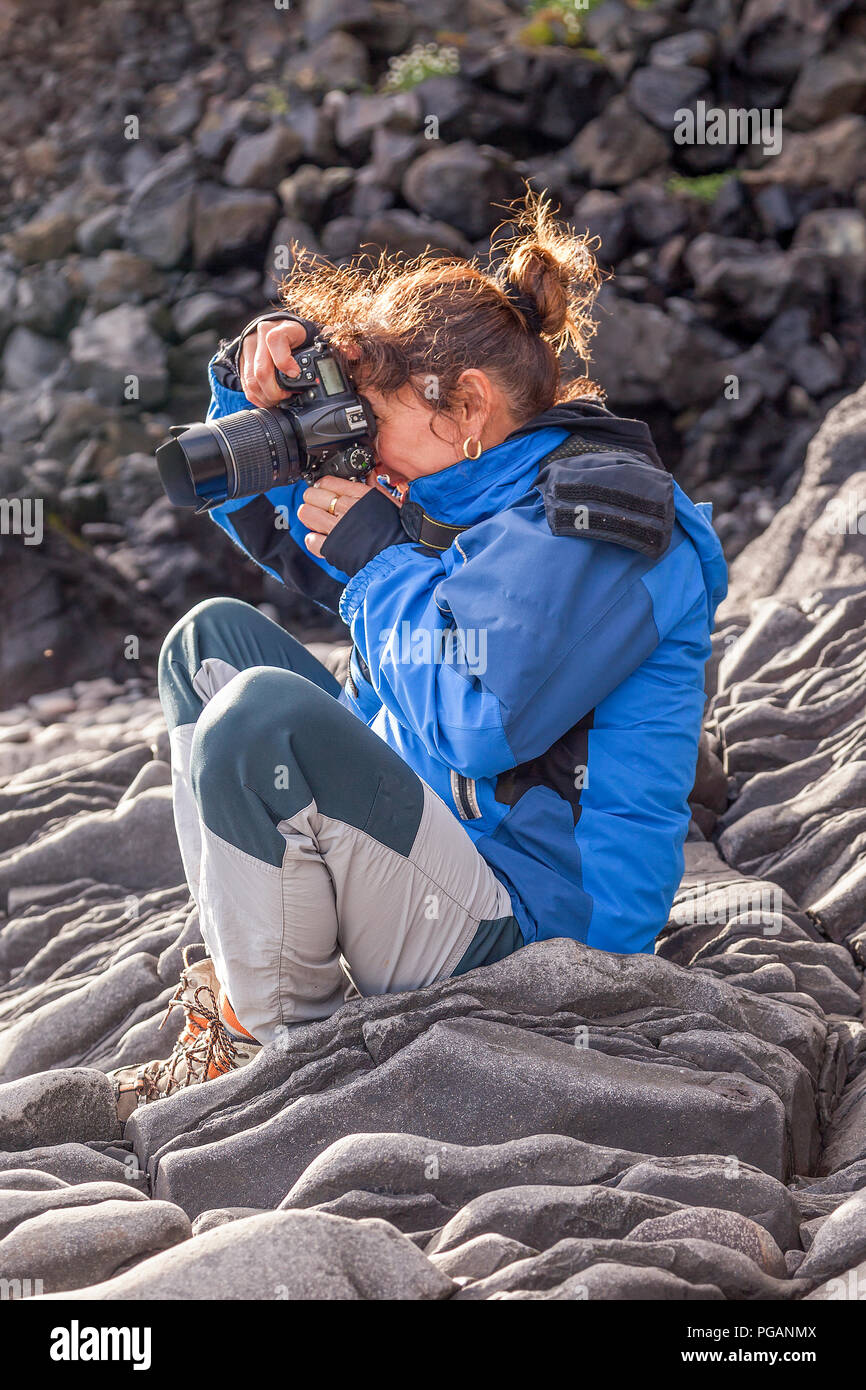 female nature photographer in action in the wild landscape of Iceland ...