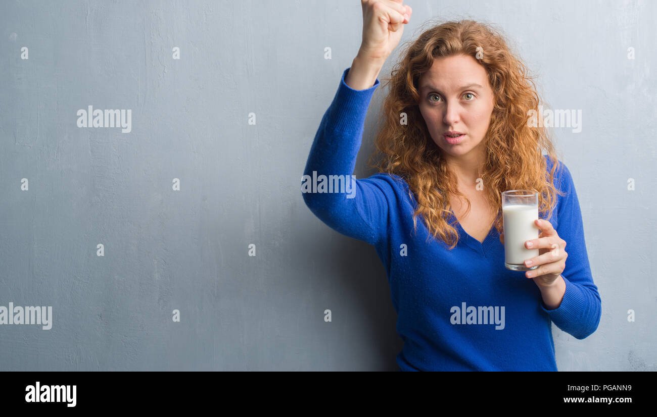 Young redhead woman drinking glass of milk annoyed and frustrated ...
