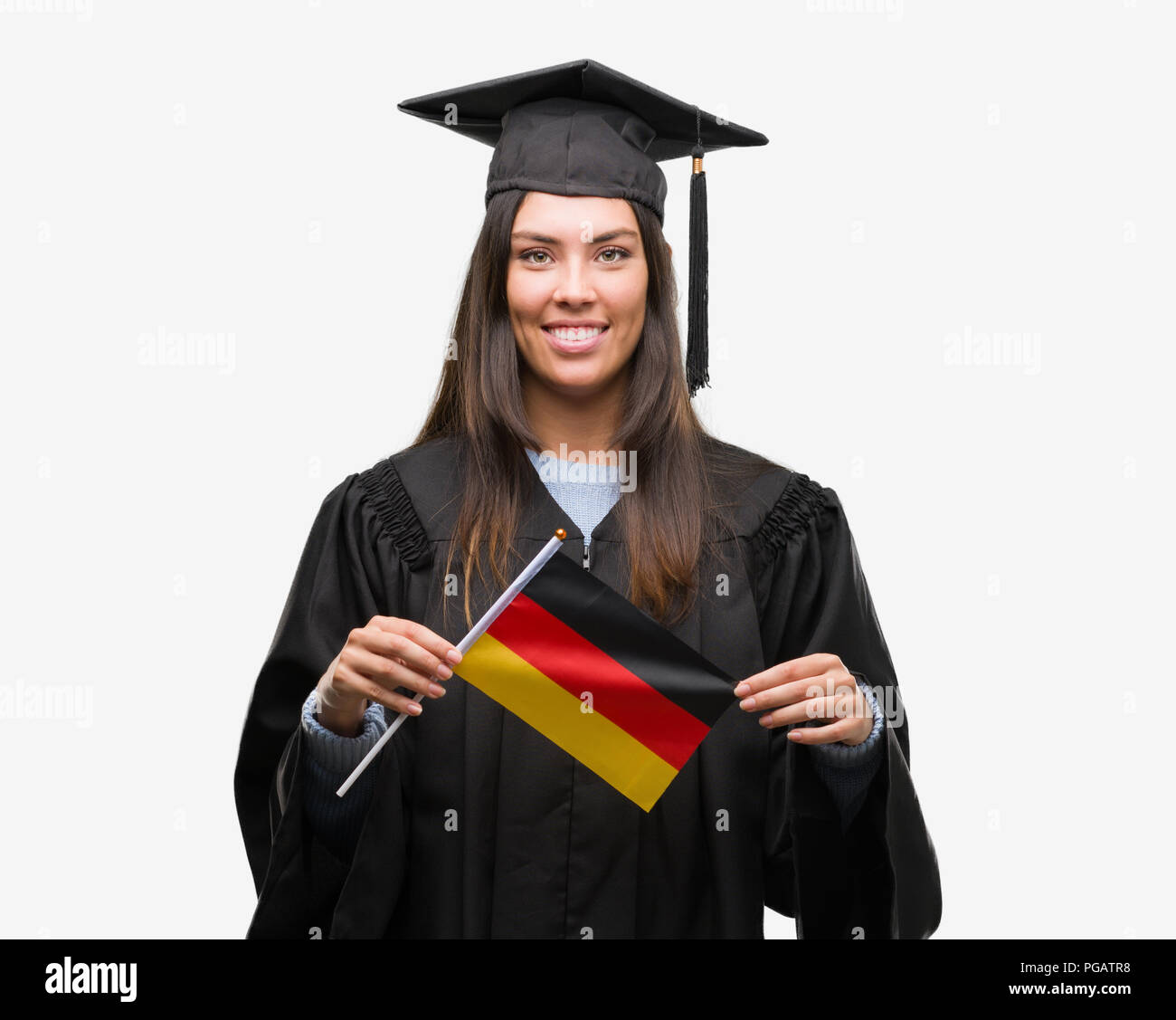 Young hispanic woman wearing graduated uniform holding flag of germany ...