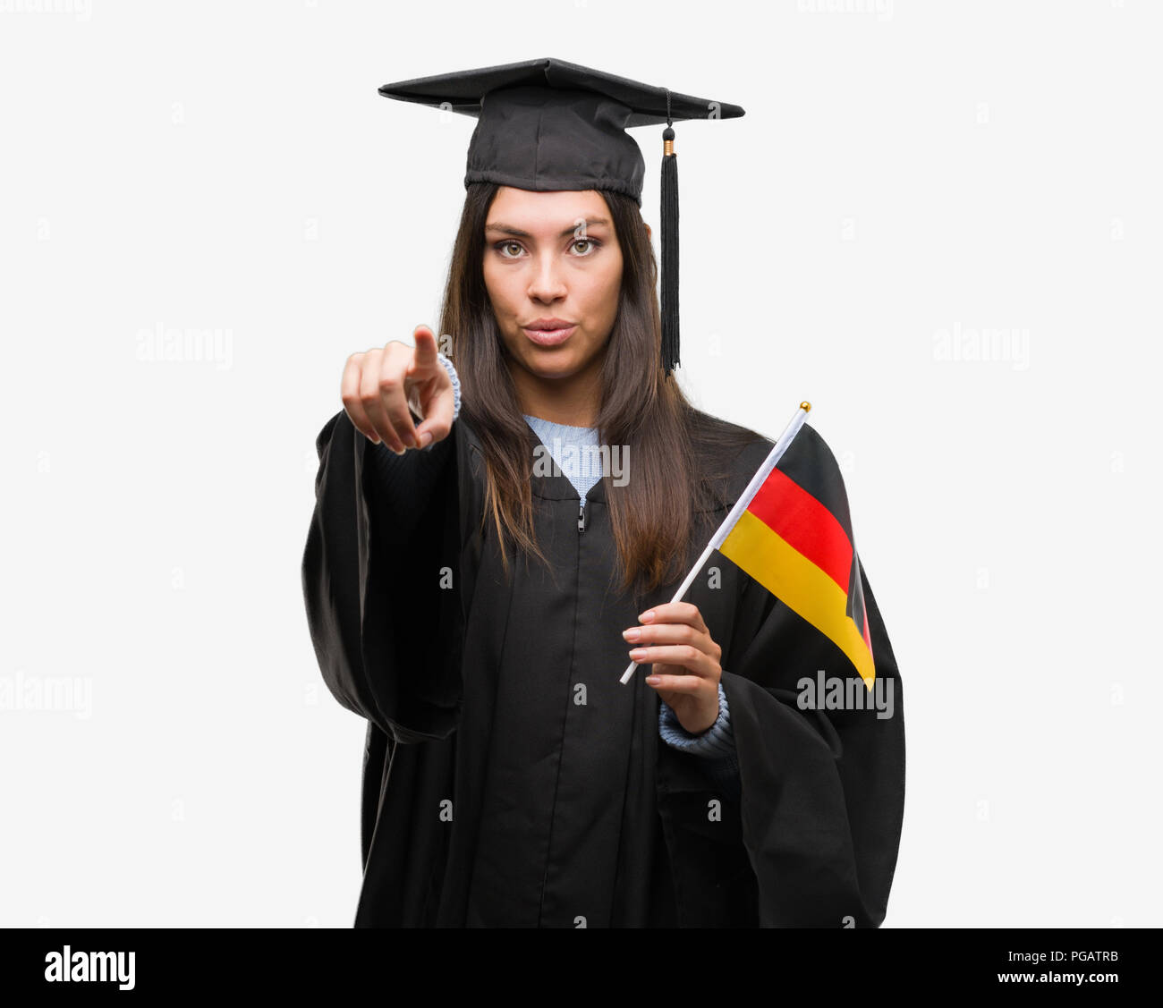 Young hispanic woman wearing graduated uniform holding flag of germany ...