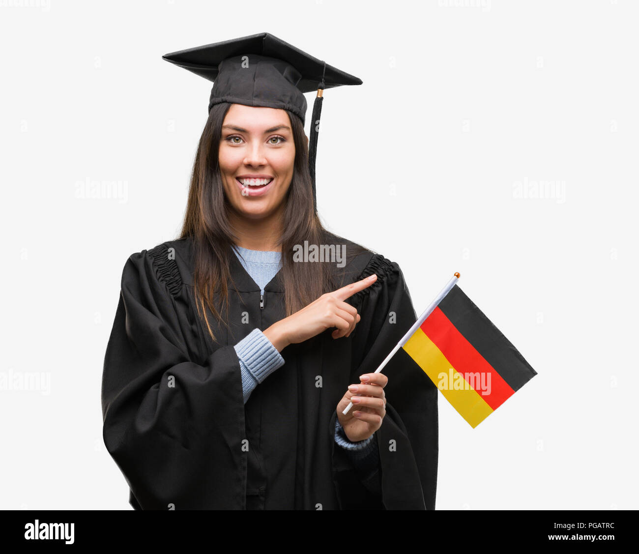 Young hispanic woman wearing graduated uniform holding flag of germany ...