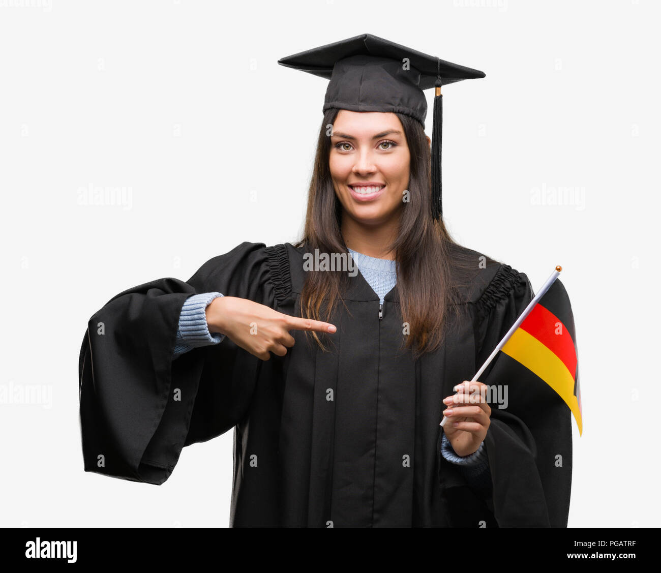 Young hispanic woman wearing graduated uniform holding flag of germany ...