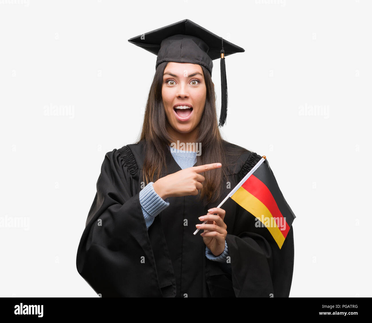 Young hispanic woman wearing graduated uniform holding flag of germany ...