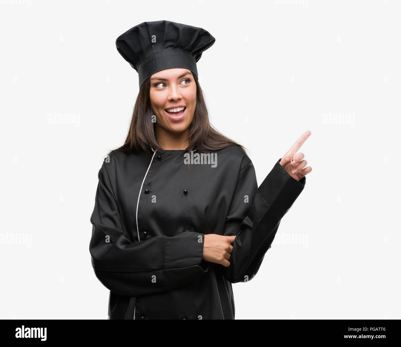 Young hispanic cook woman wearing chef uniform very happy pointing with ...