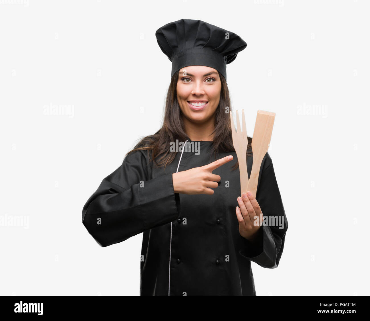 Young hispanic cook woman wearing chef uniform very happy pointing with ...