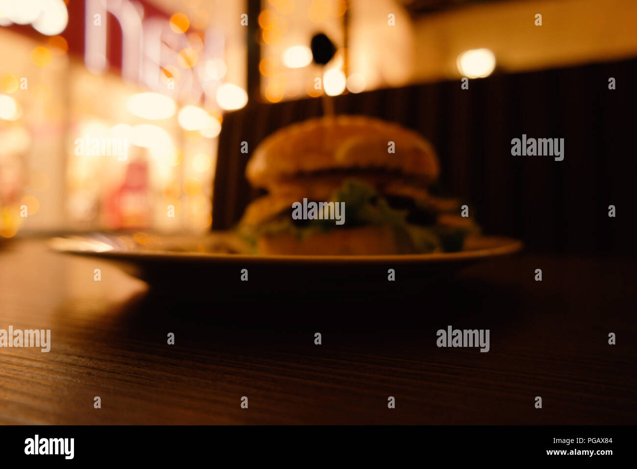 Defocused shot of ham burger on table in illuminated for christmas cafe ...