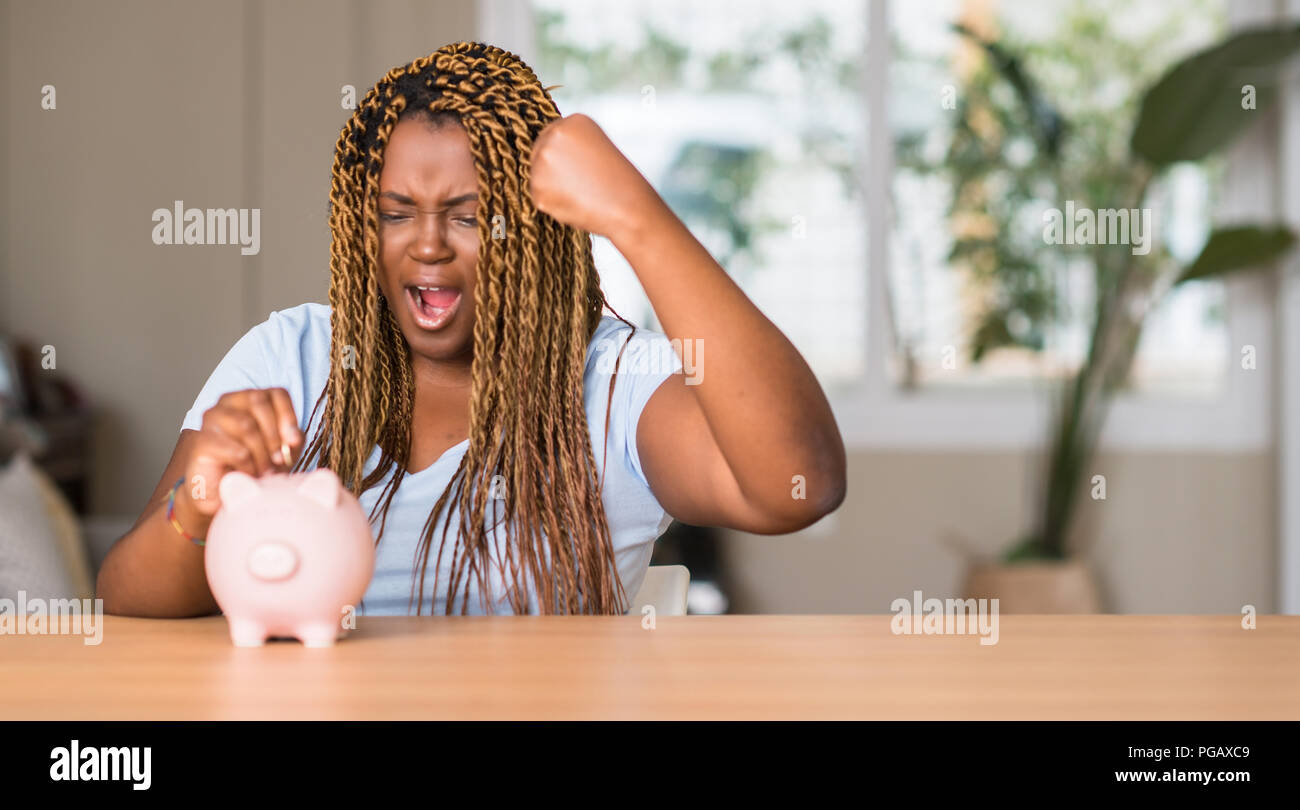 African american woman saving money with piggy bank annoyed and ...