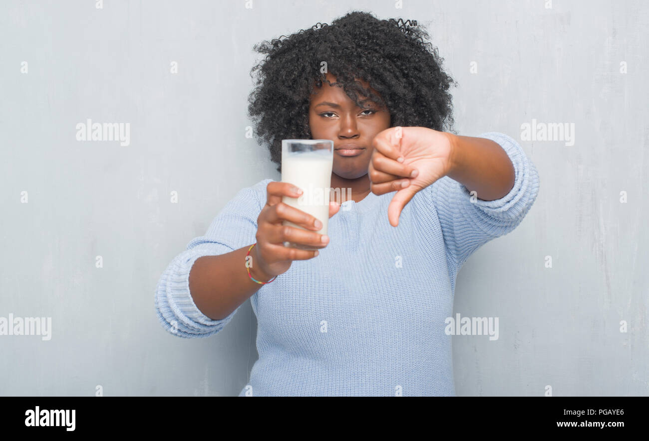 Young african american woman over grey grunge wall drinking a glass of ...
