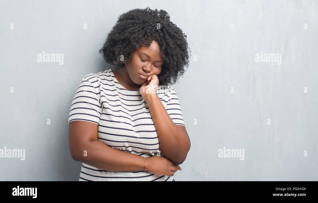 Young african american plus size woman over grey grunge wall thinking ...