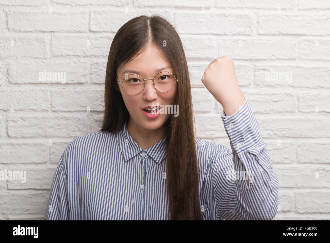 Young Chinese business woman over brick wall annoyed and frustrated ...