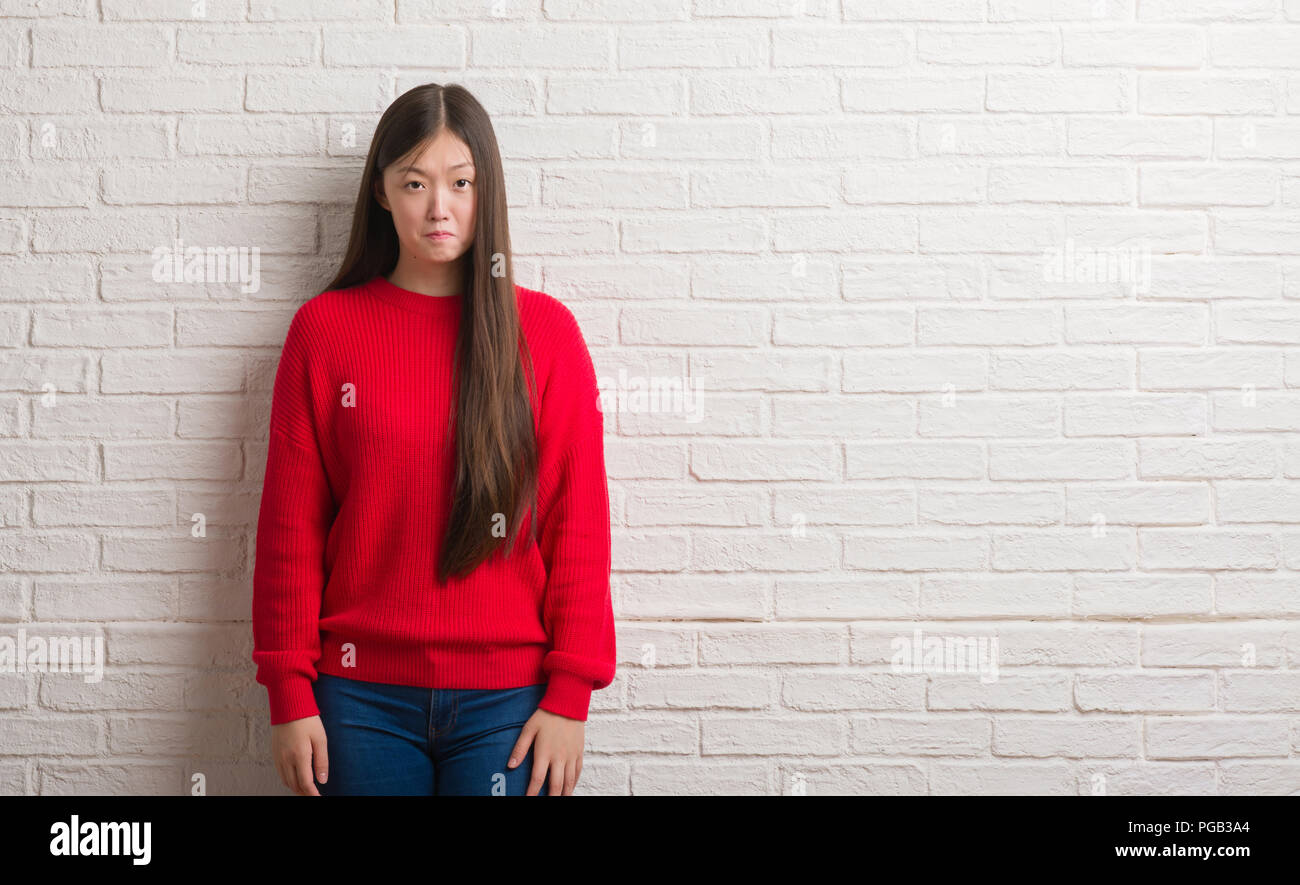 Young Chinese woman over brick wall depressed and worry for distress ...