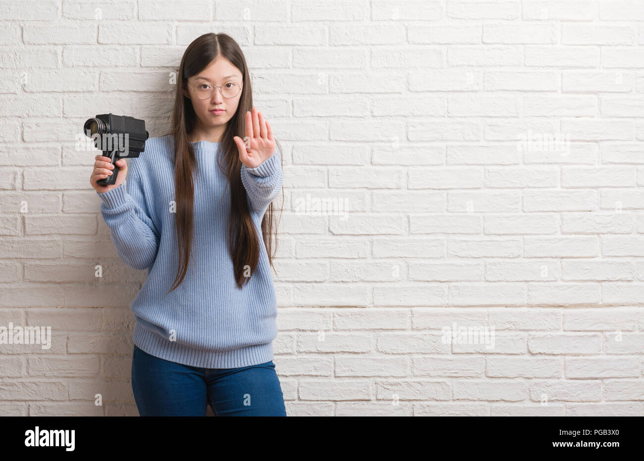 Young Chinese woman filming holding video camera with open hand doing ...