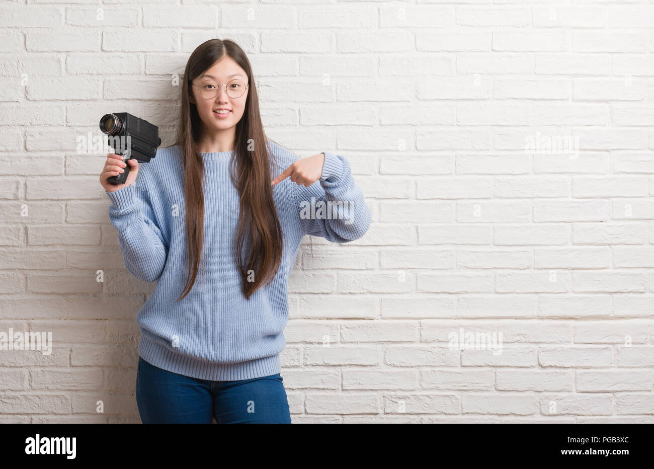 Young Chinese woman filming holding video camera with surprise face ...